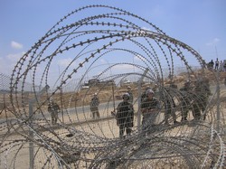 Israeli soldiers stand guard behind a security razor wire, Bil'in, 20 ...