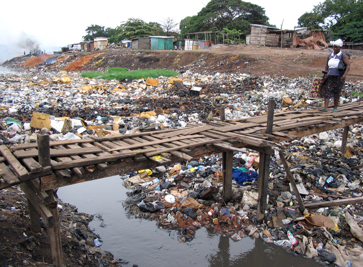 A woman with a baby cross a wooded bridge leading to Old Fadama, Accra ...