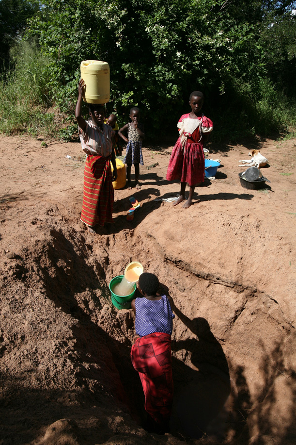 Women fetch water from a natural source in the ground, Zambia, March ...