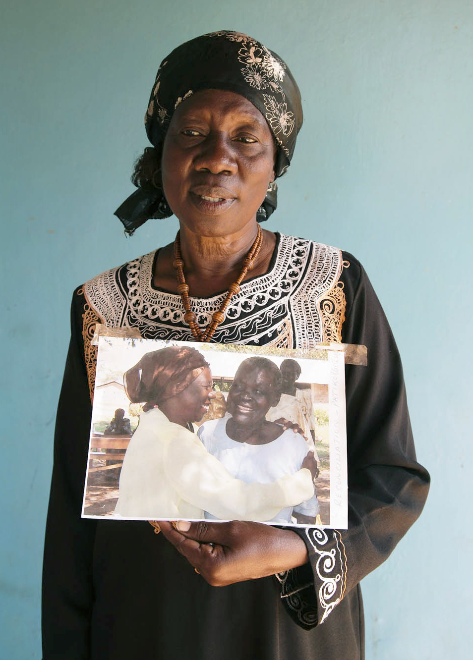 Angelina Atyam, holding up a picture of her meeting with the mother of ...