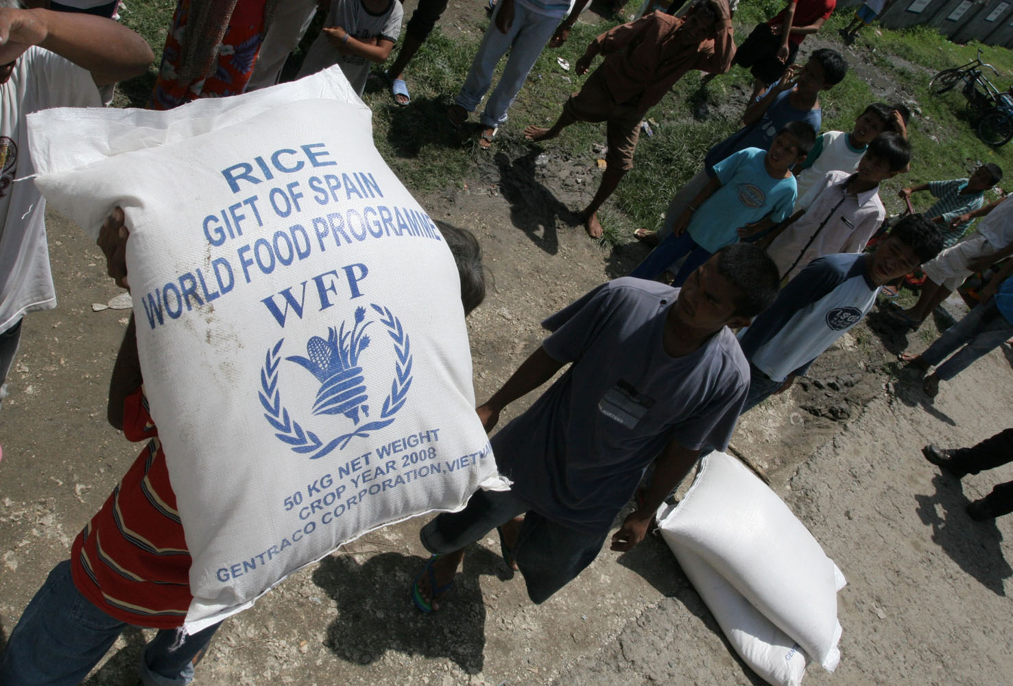 Relief workers unload sacks of rice from the World Food Program (WFP ...