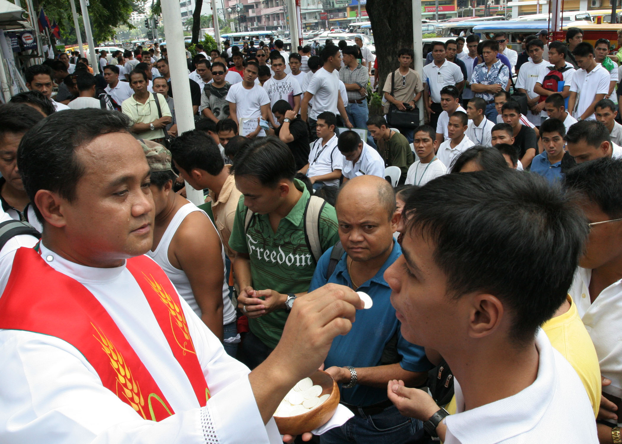 A Catholic priest gives holy communion to Filipino seafarers during a ...