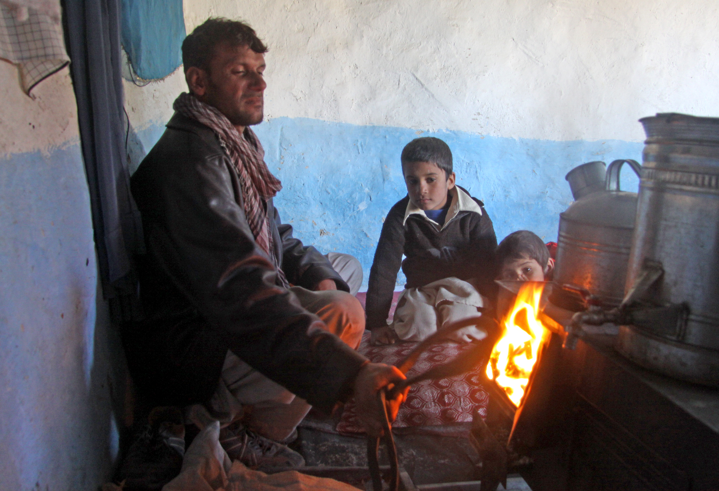A returnee family keeps warm by burning plastic waste in their Bukhari ...