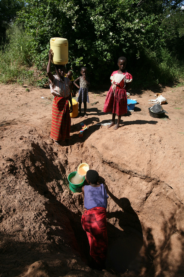 Women fetch water from a natural source in the ground, Zambia, March ...