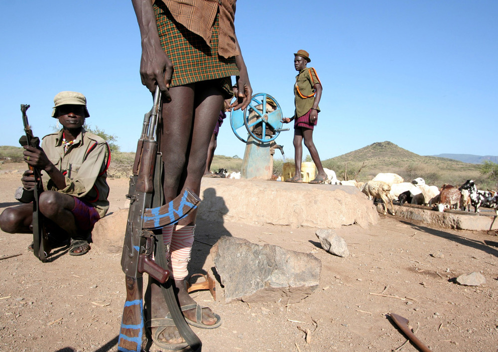Turkana men armed with AK-47 rifles next to a water pump, Oropoi ...
